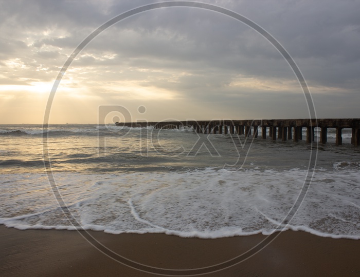 Image of A Pier Into The Sea Long View Shot with Waves in Fore Ground ...