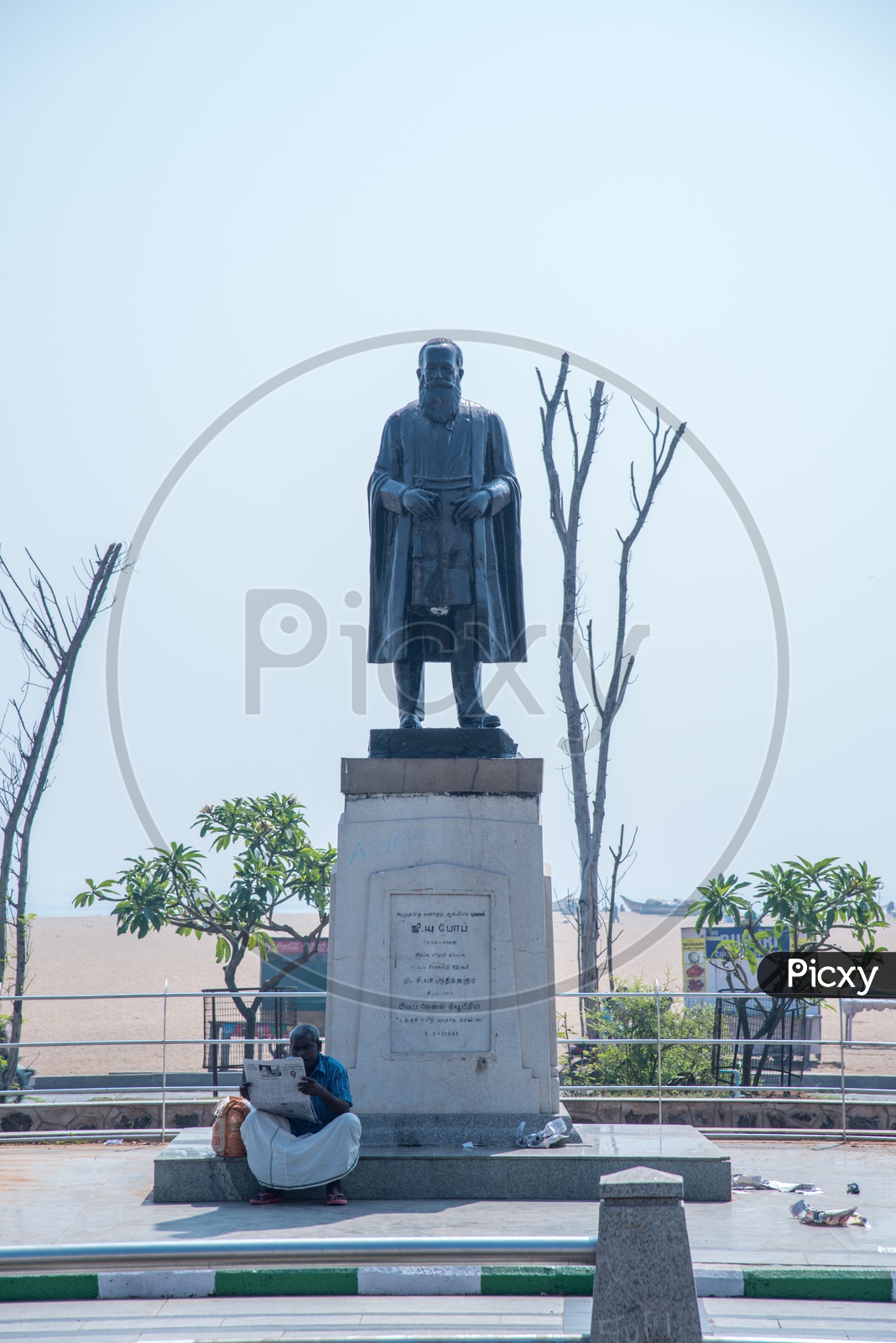 Image of A commuter reading news paper under GU Pope Statue-FP323924-Picxy