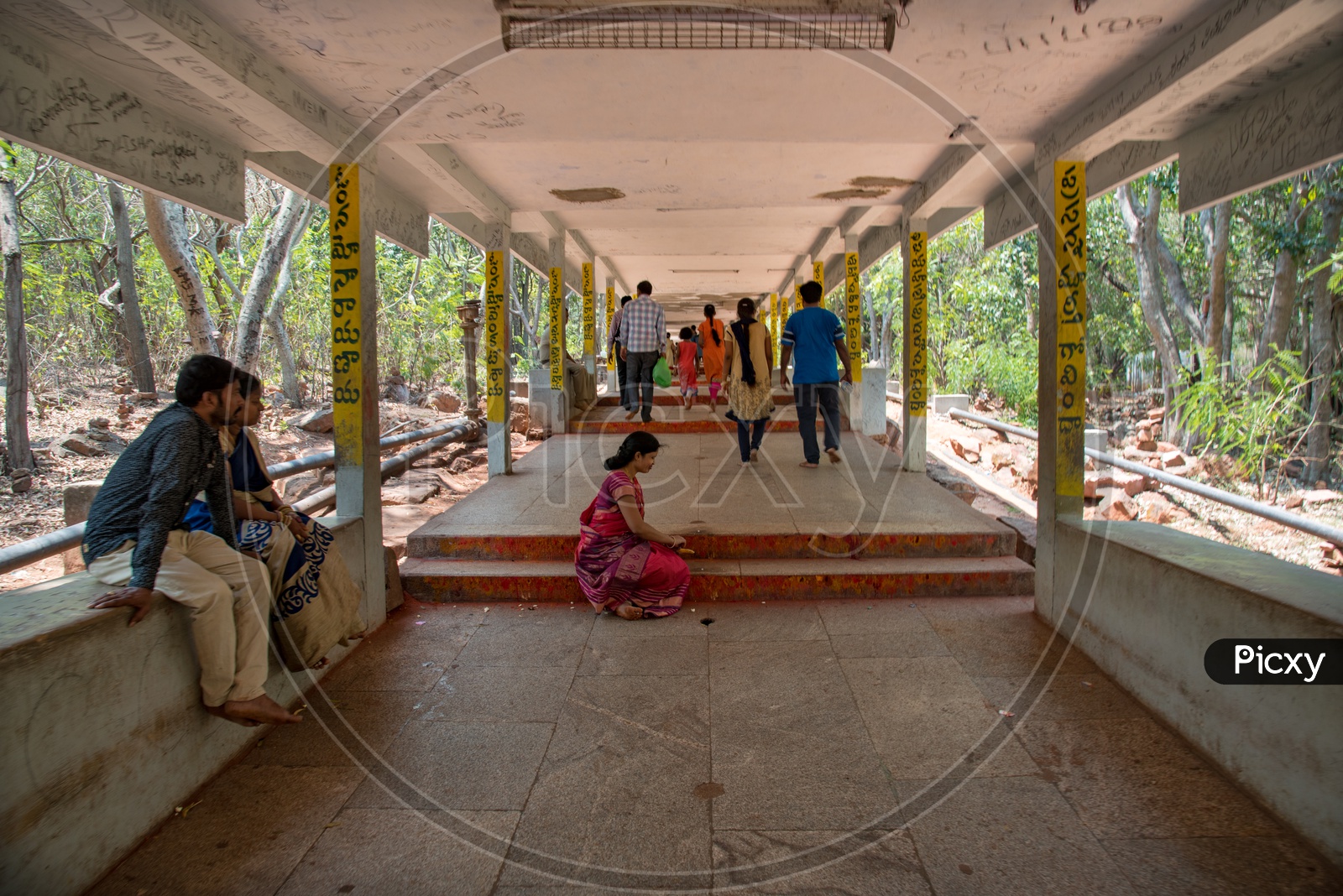 Image of A woman devotee lighting up a diya on tirumala walk way ...