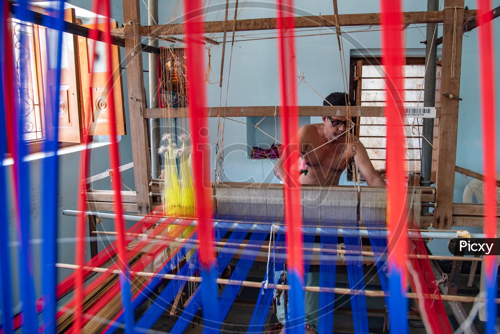 Image of Artisan weaver working on hand operated spindle weaving ...