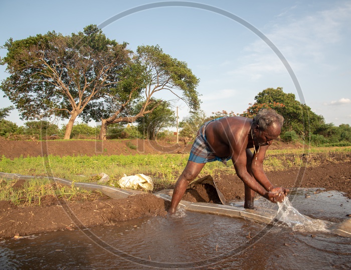 Image of a farmer drinking water from a pumpset in his field-QB358126-Picxy