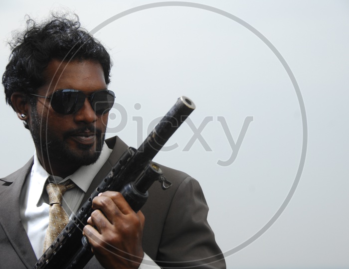 Image of Telugu/Tamil/South Indian actor holding a gun. Behind the ...