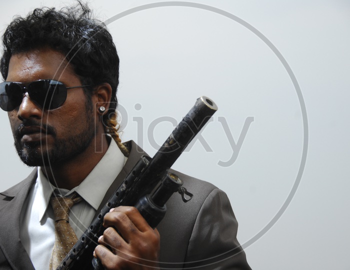 Image of Telugu/Tamil/South Indian actor holding a gun. Behind the ...