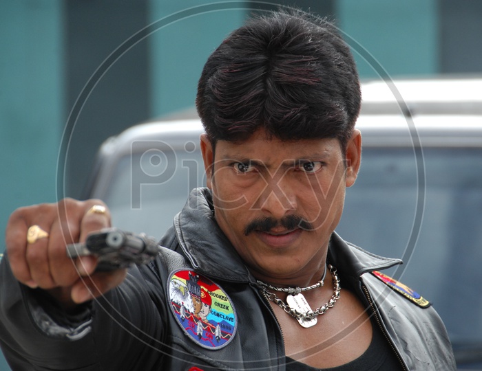 Image of Telugu/Tamil/South Indian actor holding a gun. Behind the ...