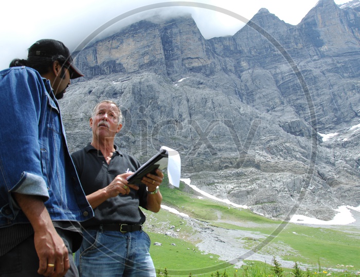 Image of Two men talking near a mountain area, clouds seen at a far ...
