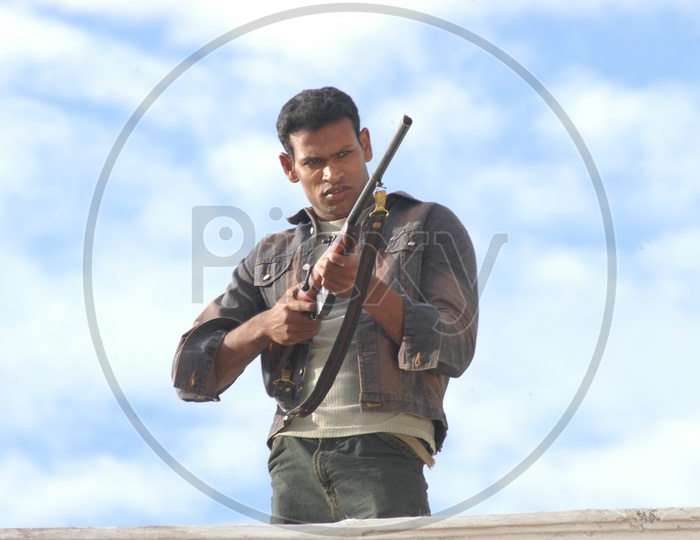 Image of Telugu/Tamil/South Indian actor holding a gun. Behind the ...