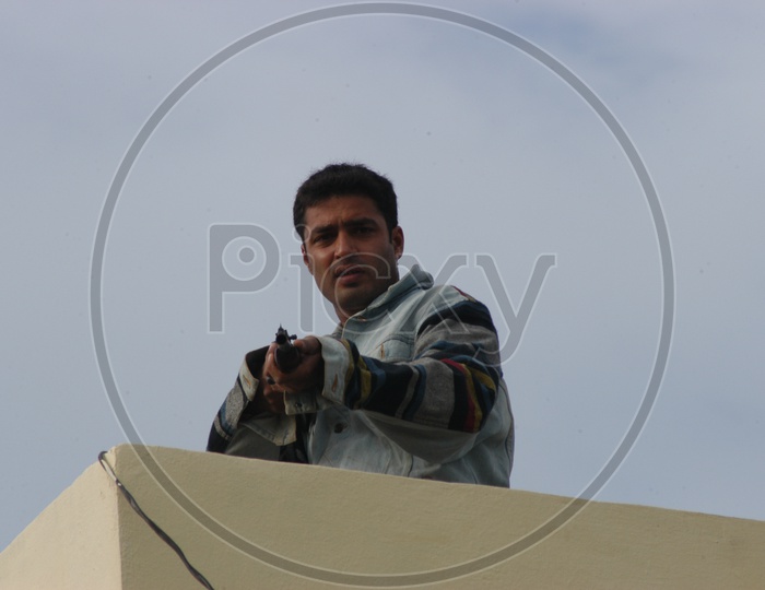 Image of Telugu/Tamil/South Indian actor holding a gun. Behind the ...