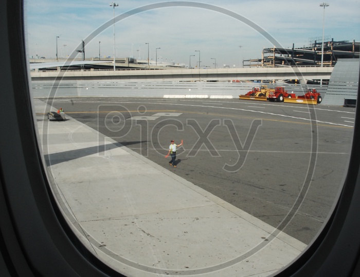 Image of Ground crew standing on runway captured from flight window ...