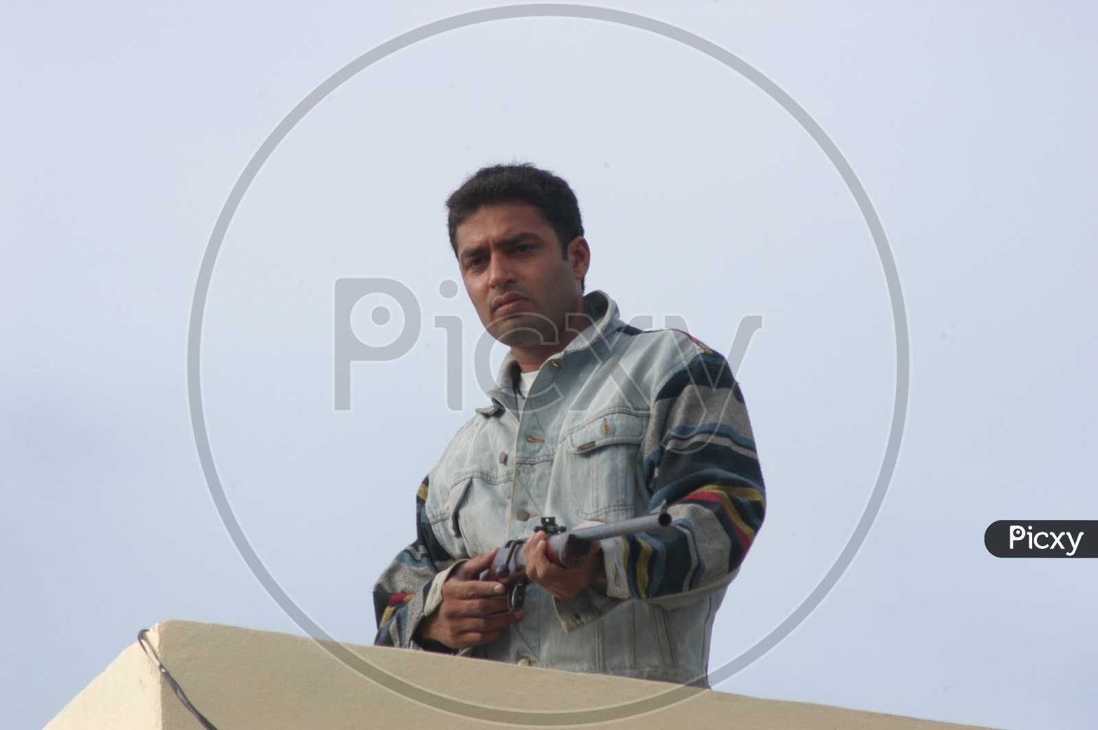 Image of Telugu/Tamil/South Indian actor holding a gun. Behind the ...