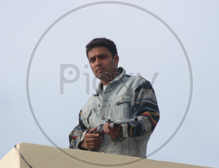 Image of Telugu/Tamil/South Indian actor holding a gun. Behind the ...