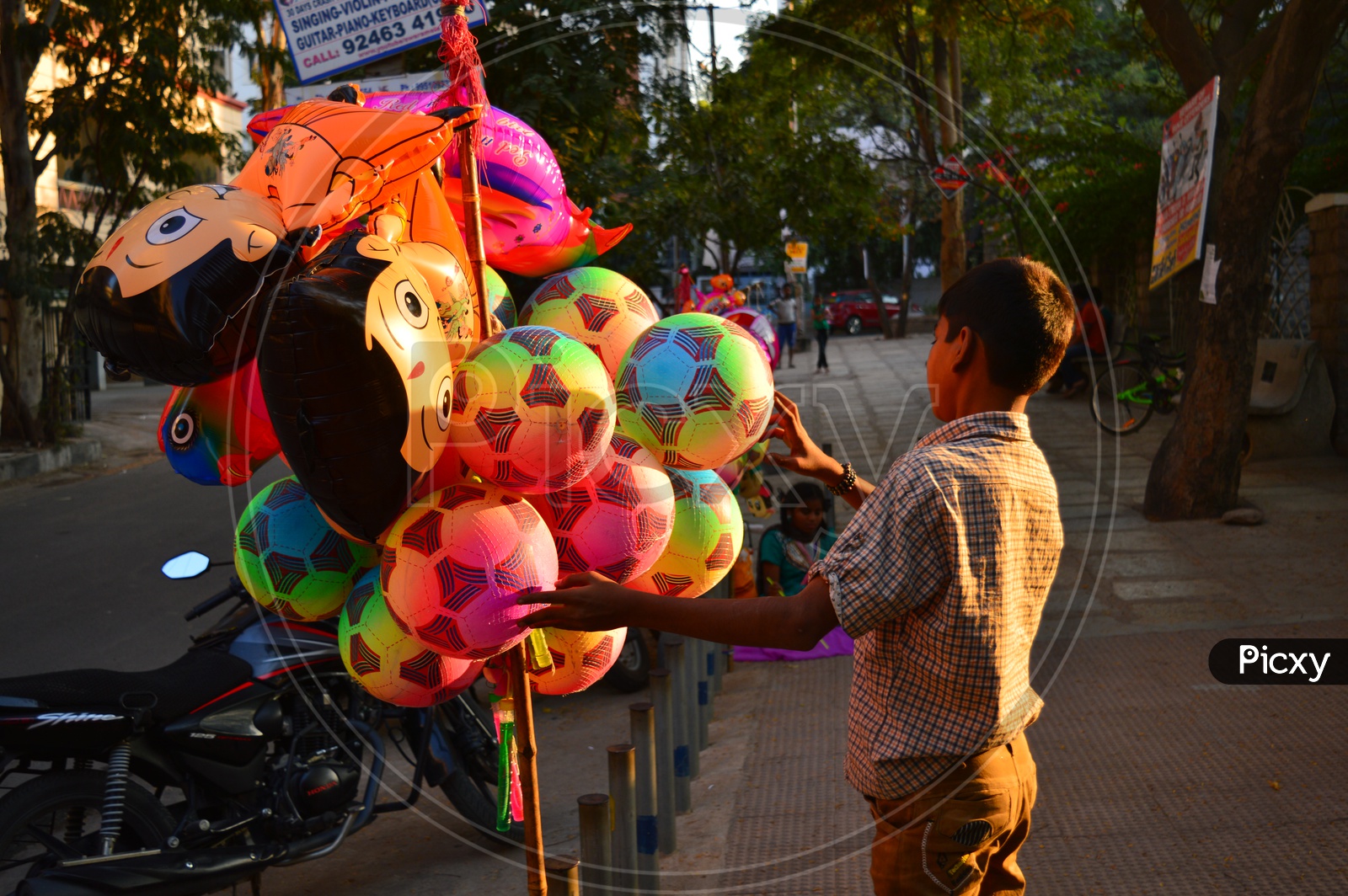 Image of A Small Boy vendor Selling toys on a Road-OH523125-Picxy