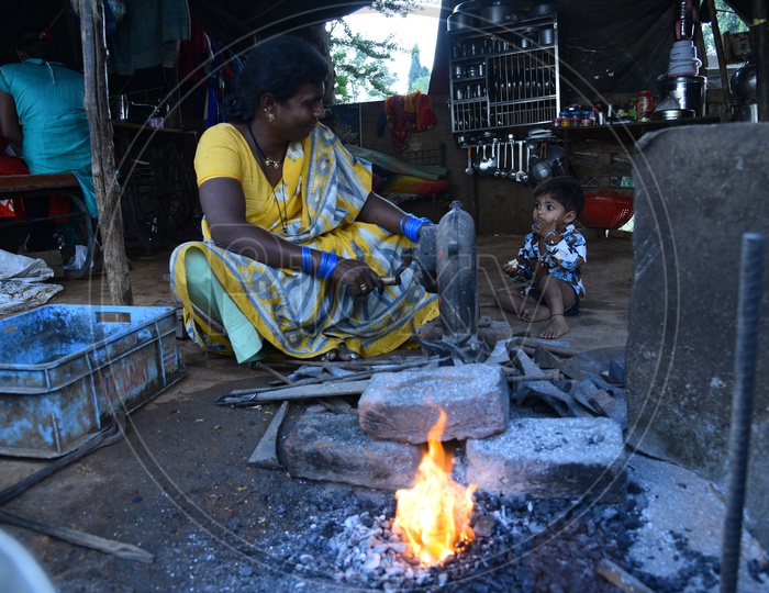Image of Indian Blacksmith Playing with kid while Shaping the Iron ...