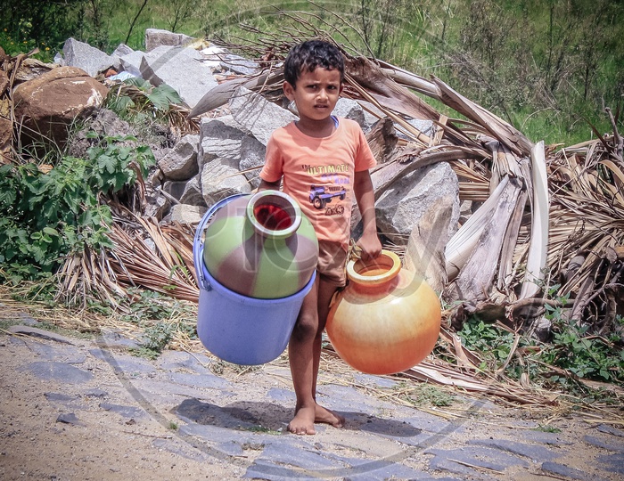 Image of A child carrying plastic buckets and plastic pots-XK234391-Picxy