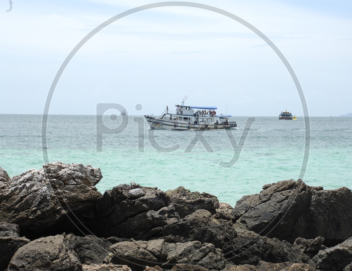 Image of A boat seen at a distance in a beach through the rocks ...