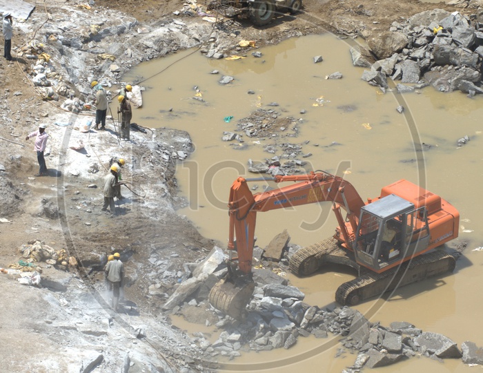 Image of Bulldozer operator working alongside the labourers drilling at ...