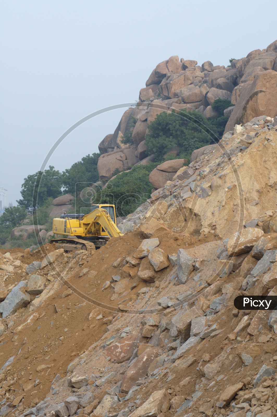 Image of Bulldozer quarrying the construction rocks alongside the hill ...
