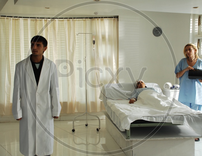 Image of A nurse checking the patient while the doctors stand aside ...