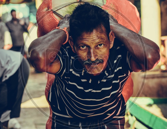 Image of Hard Woker, a man lifting vegetables in a sack-RA071075-Picxy