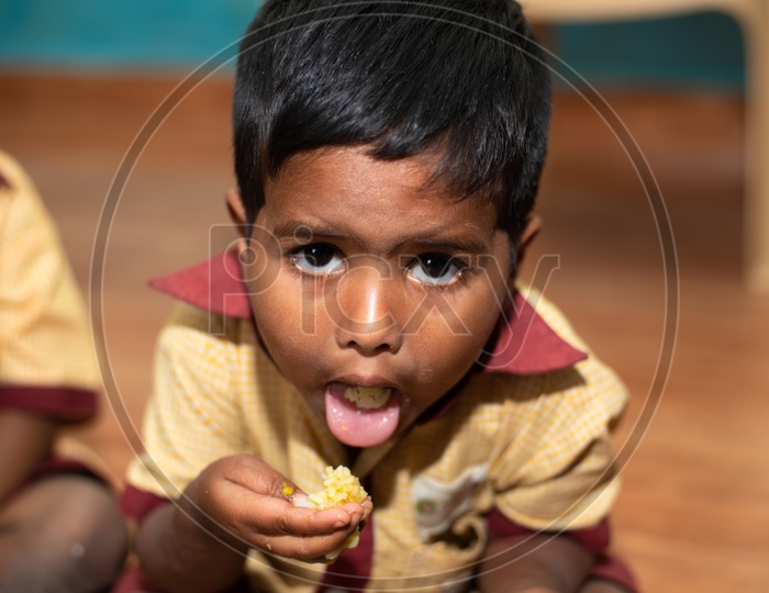 Image of A young boy eating his mid day meal in an Anganwadi center ...