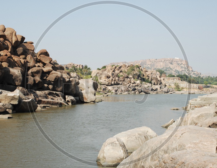 Image of Hampi temple ruins in between the mountain rocks and Lake ...