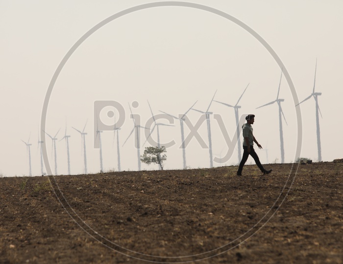 Image of A man Walking alone On Barren Lands With Wind Mills on ...