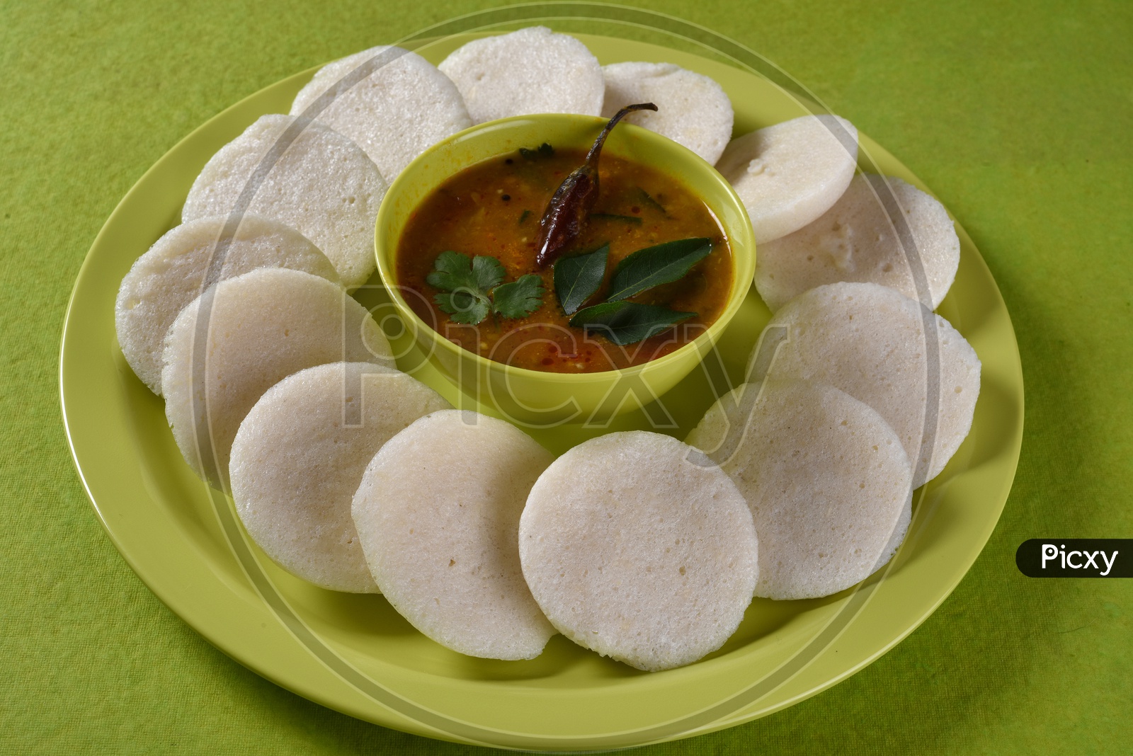 Image of Idli with Sambar in bowl on green background-ZI281515-Picxy