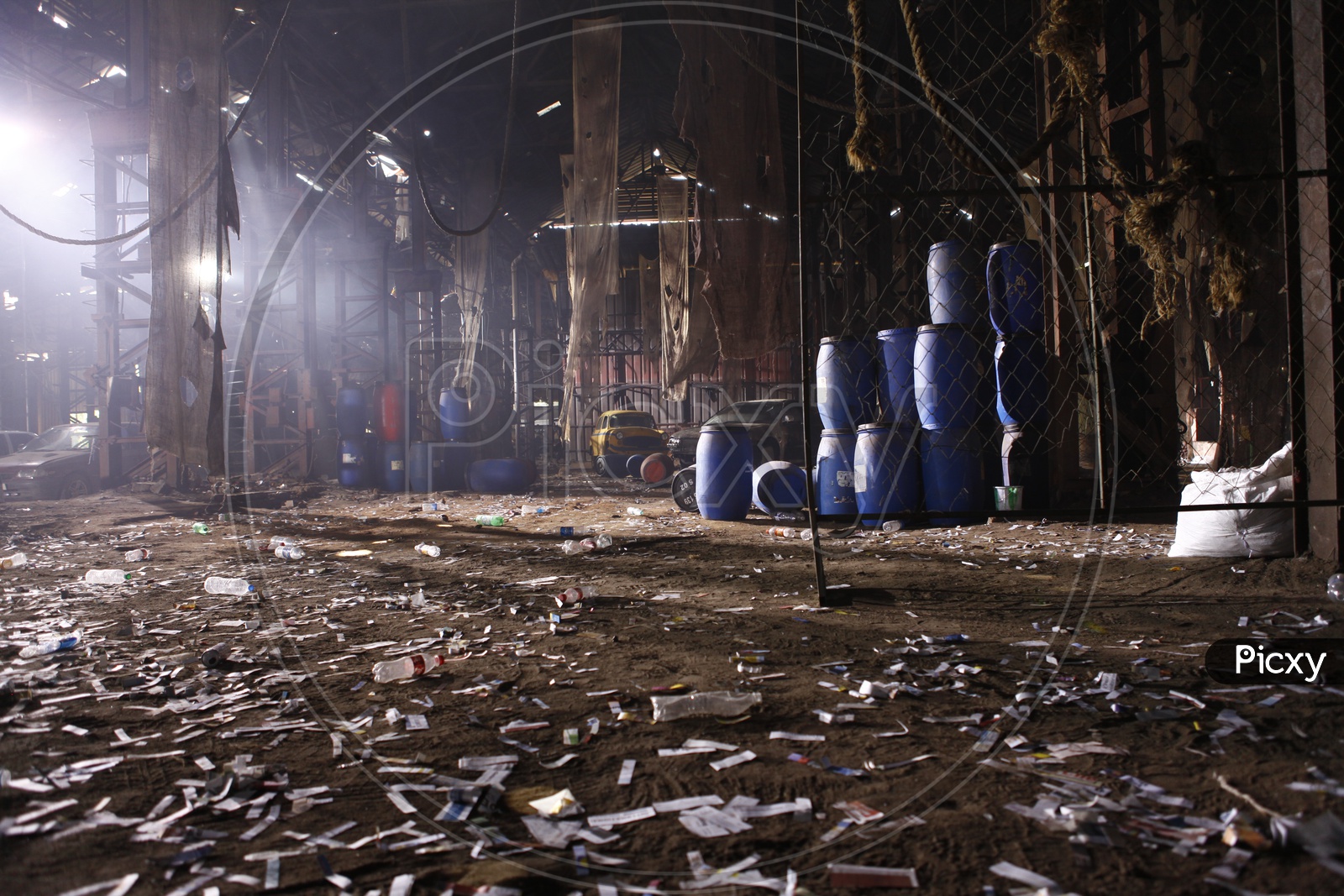 Image of Plastic drums, old cars and litter in an old factory godown ...
