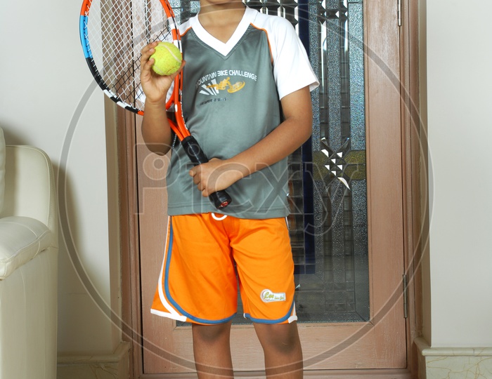 Image of Indian boy with sportswear holding a tennis racket and ball ...