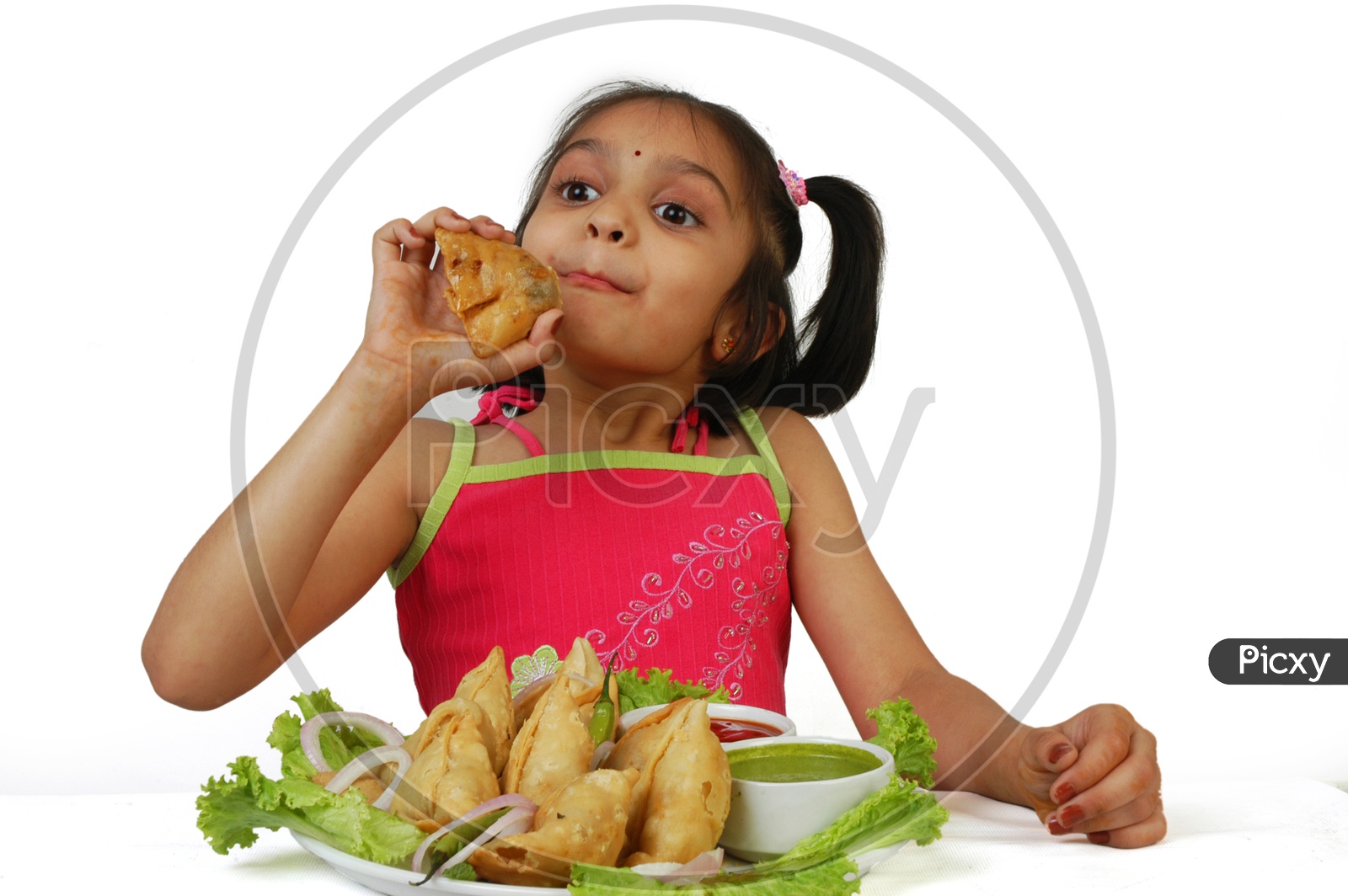 Image of Indian little girl eating samosa-HM752357-Picxy
