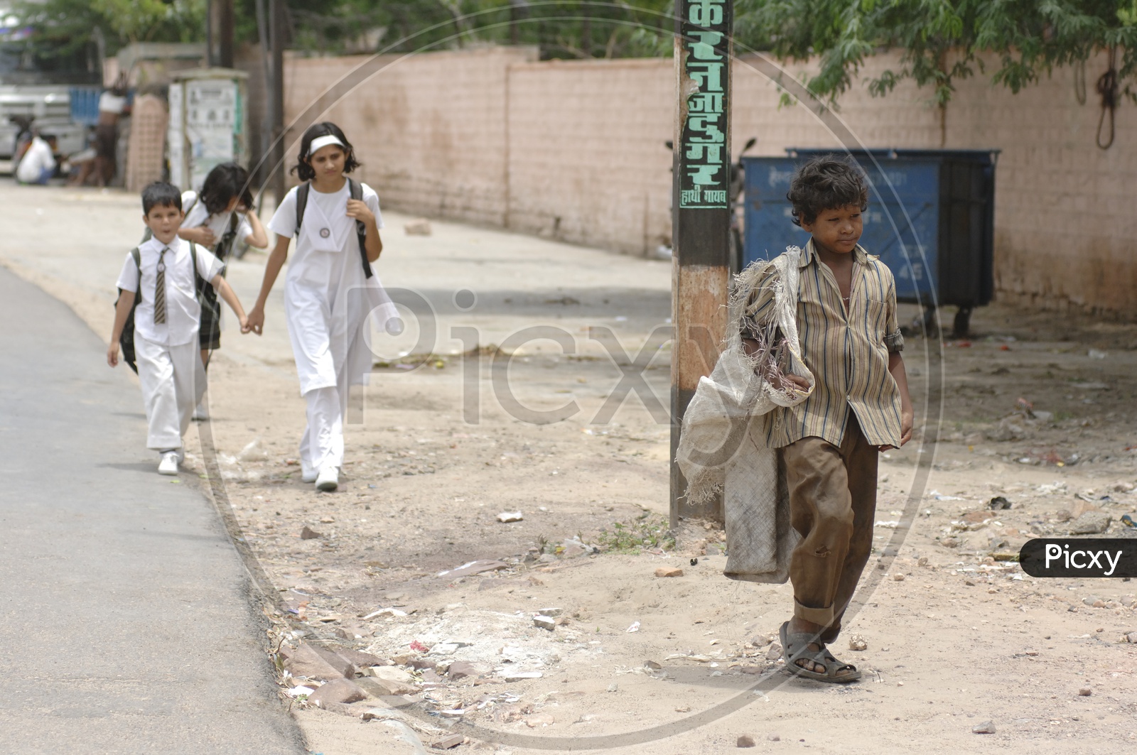 Image of Rag picker boy child in front of the school kids-LU538674-Picxy