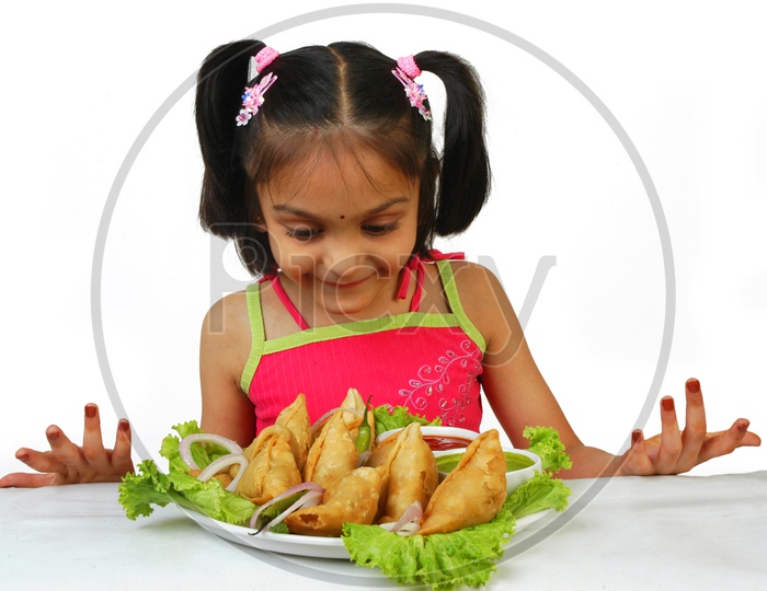 Image of Indian little girl with samosas served in a plate-BK678624-Picxy