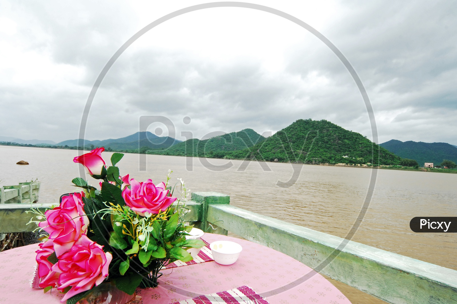Image of Roses on a table near a river with hills in the background ...