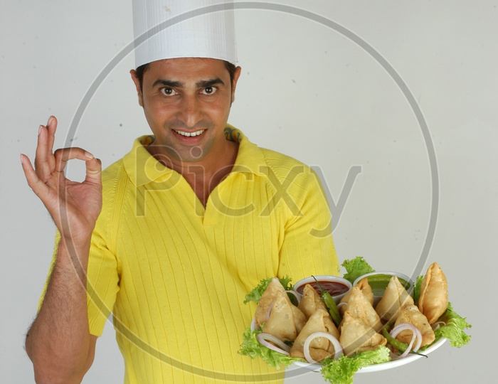 Image of An Indian Chef In Kitchen Apron And Cap Holding Samosas Plate ...