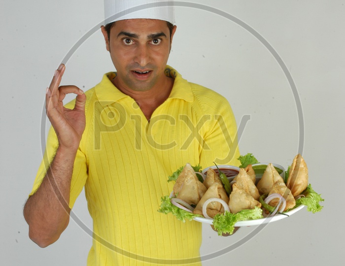 Image of An Indian Chef In Kitchen Apron And Cap Holding Samosas Plate ...