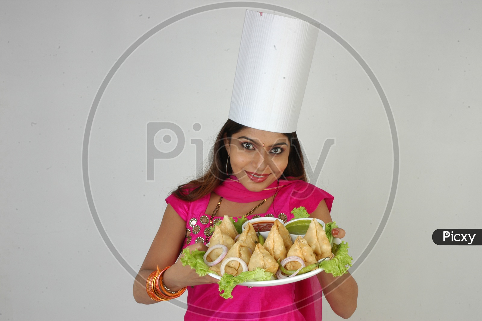 Image of An Indian Woman Chef In Kitchen Apron And Cap Holding Samosas ...