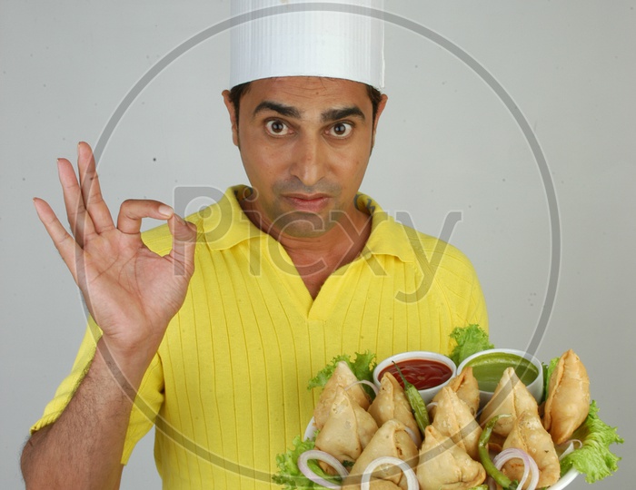 Image of An Indian Chef In Kitchen Apron And Cap Holding Samosas Plate ...