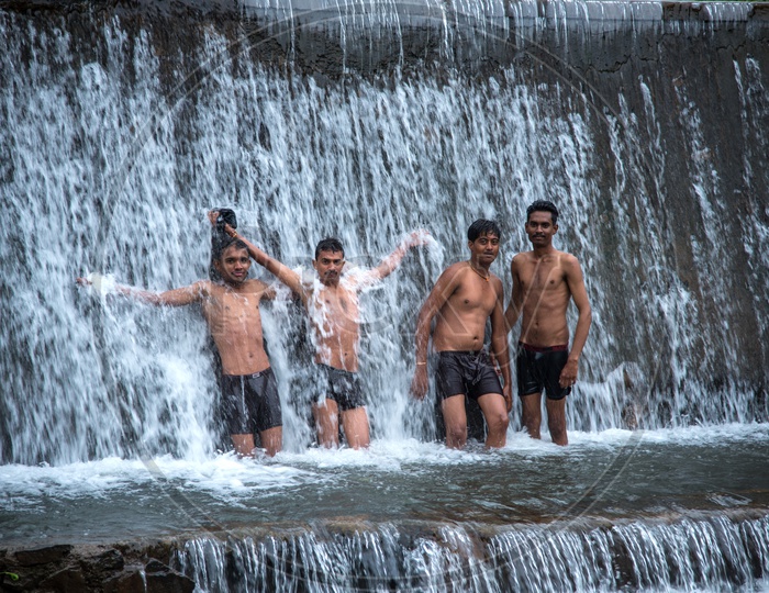 Image of A Group Of People Bathing And Playing In Water Flowing on the ...