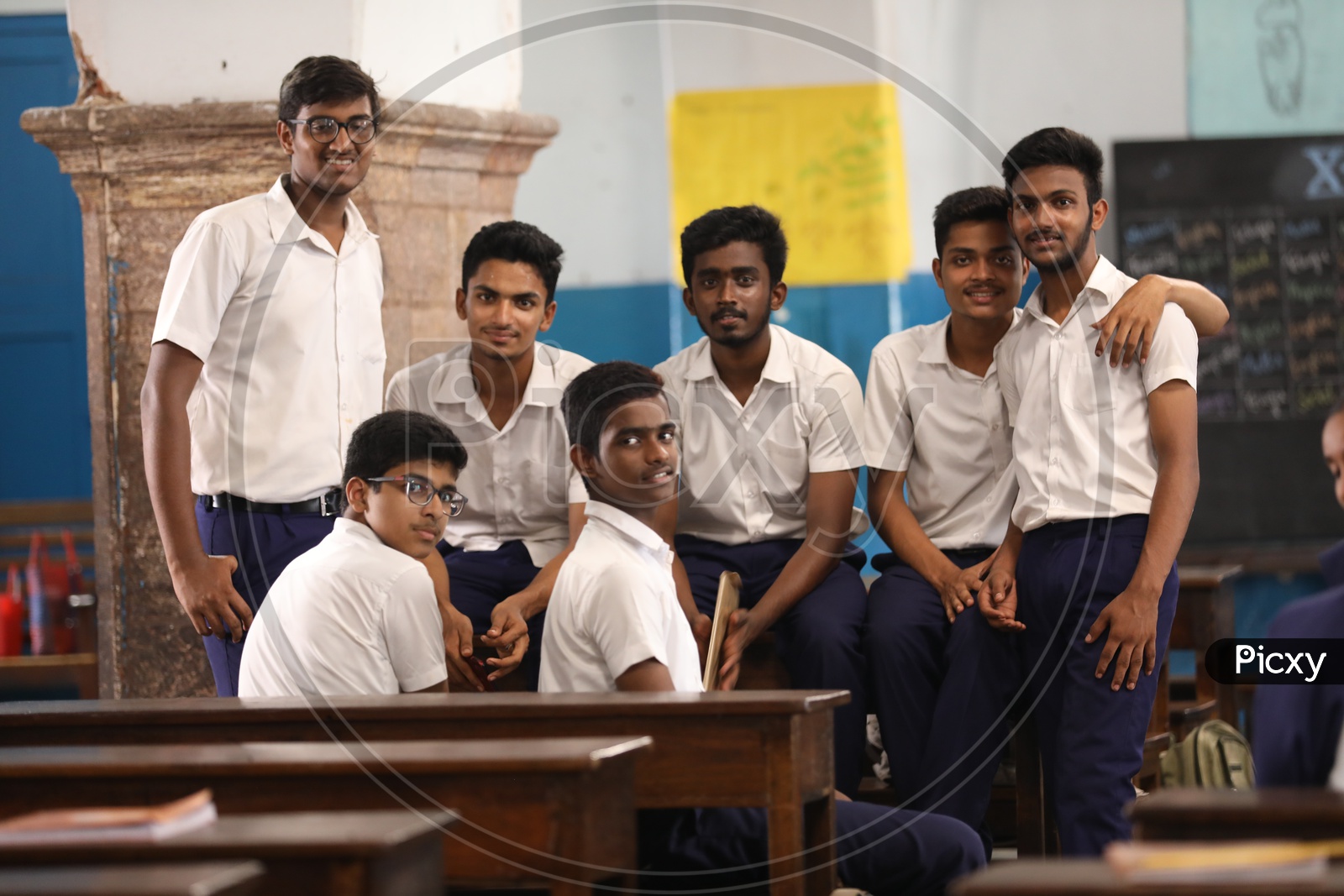 Image of School Students Posing By Sitting on Benches In a Classroom ...