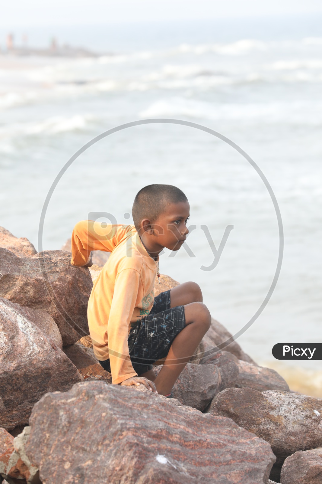 Image of A Boy Sitting On a Beach And Watching The Sea Waves-CB700795-Picxy