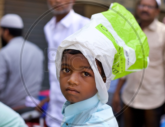Image of A kid with plastic cover as a hat on his head.-ZI183616-Picxy