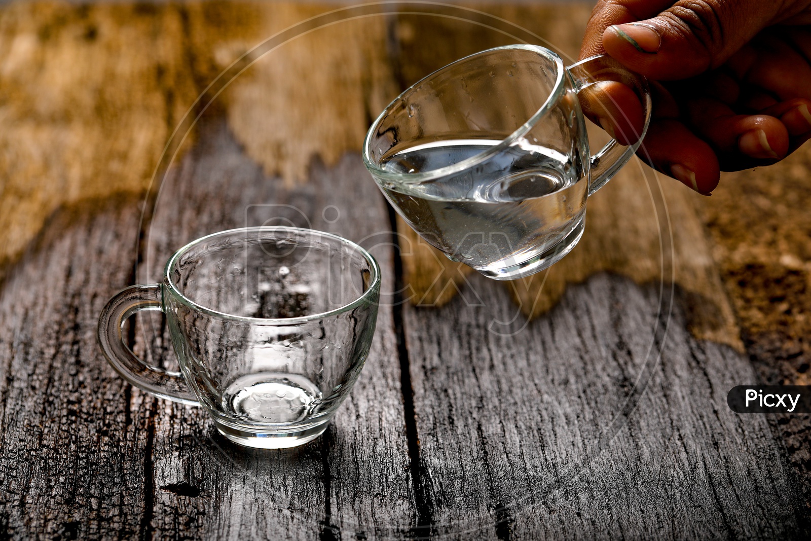 Image of Water Filled In an Glass Tea Cup On an Wooden Table-YF863556-Picxy