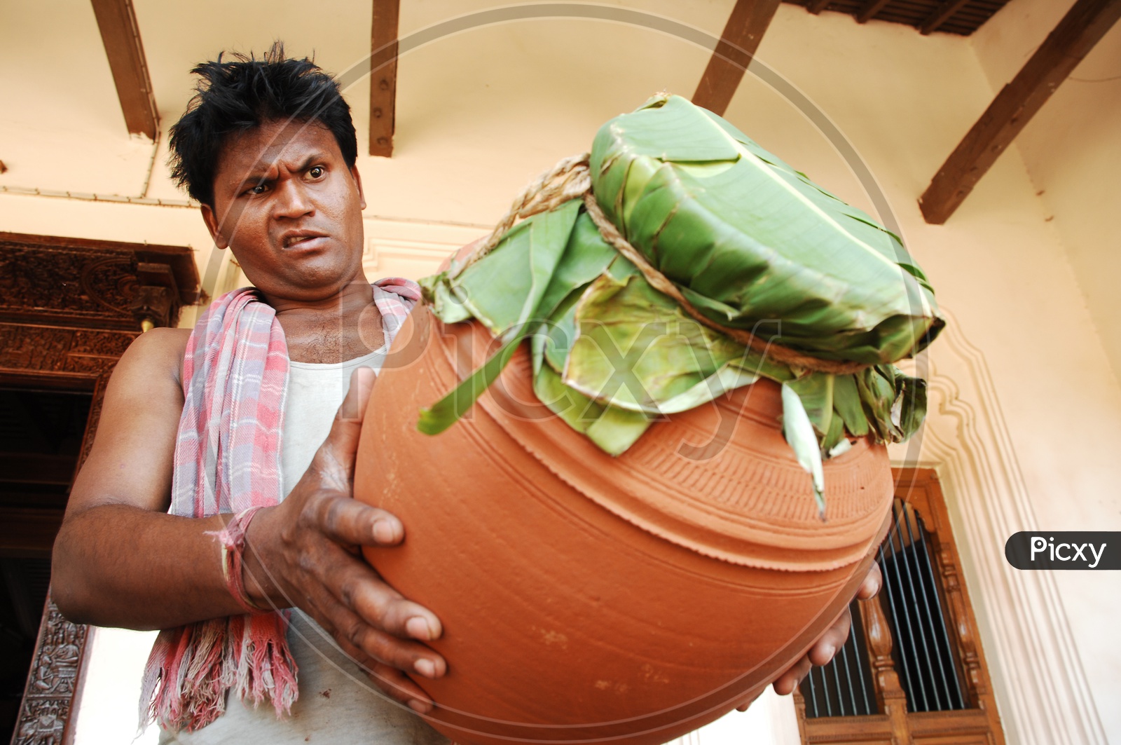 Image of A Man Holding a Pot Covered With Banana Leaf-FQ423474-Picxy