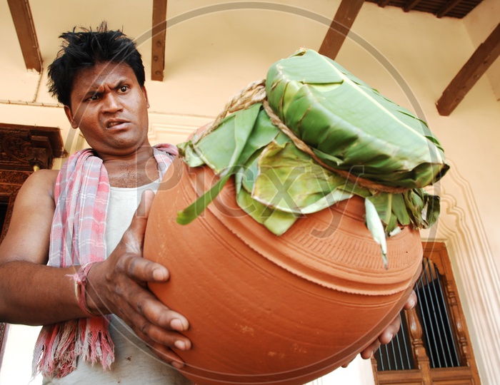 Image of A Man Holding a Pot Covered With Banana Leaf-FQ423474-Picxy
