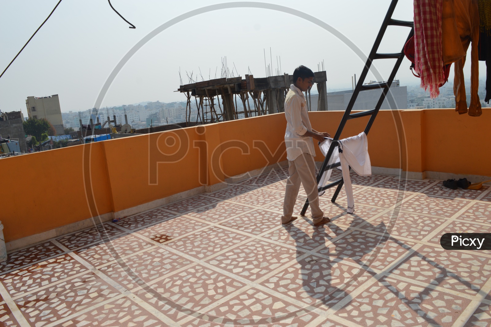Image of A Man Drying Clothes n a Terrace Ladder-MV845620-Picxy