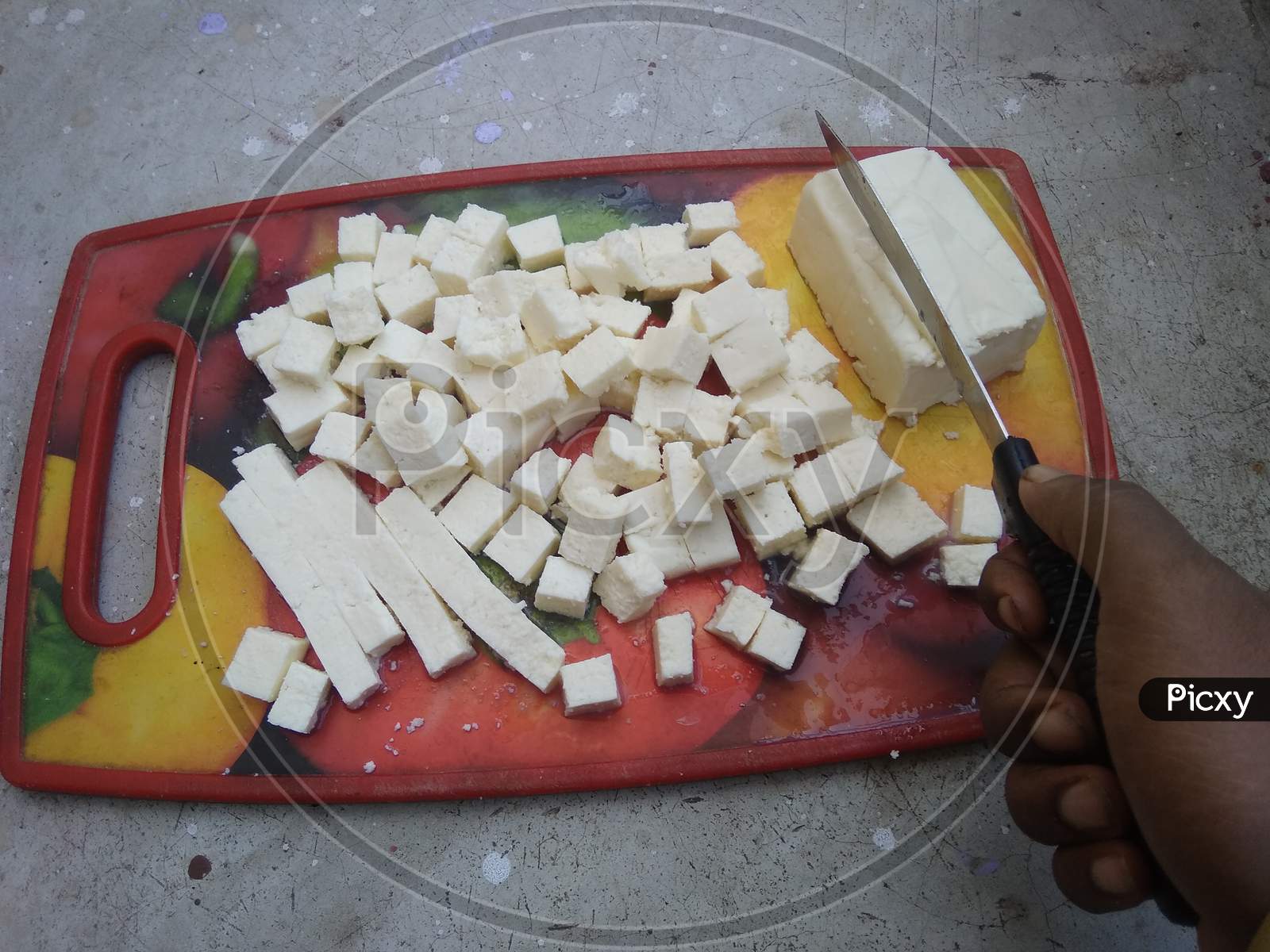 Image of Paneer, cheese cutting with knife on colorful chopping board ...