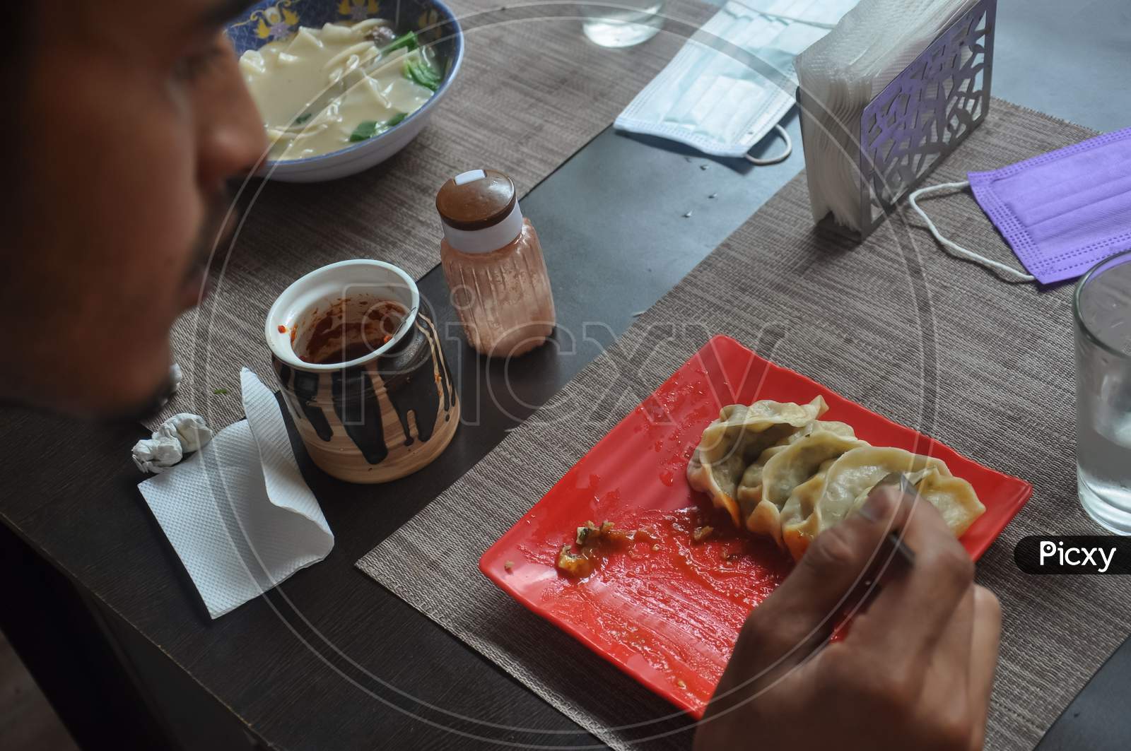 Image of Back view of a south asian young man eating momos in fast food ...