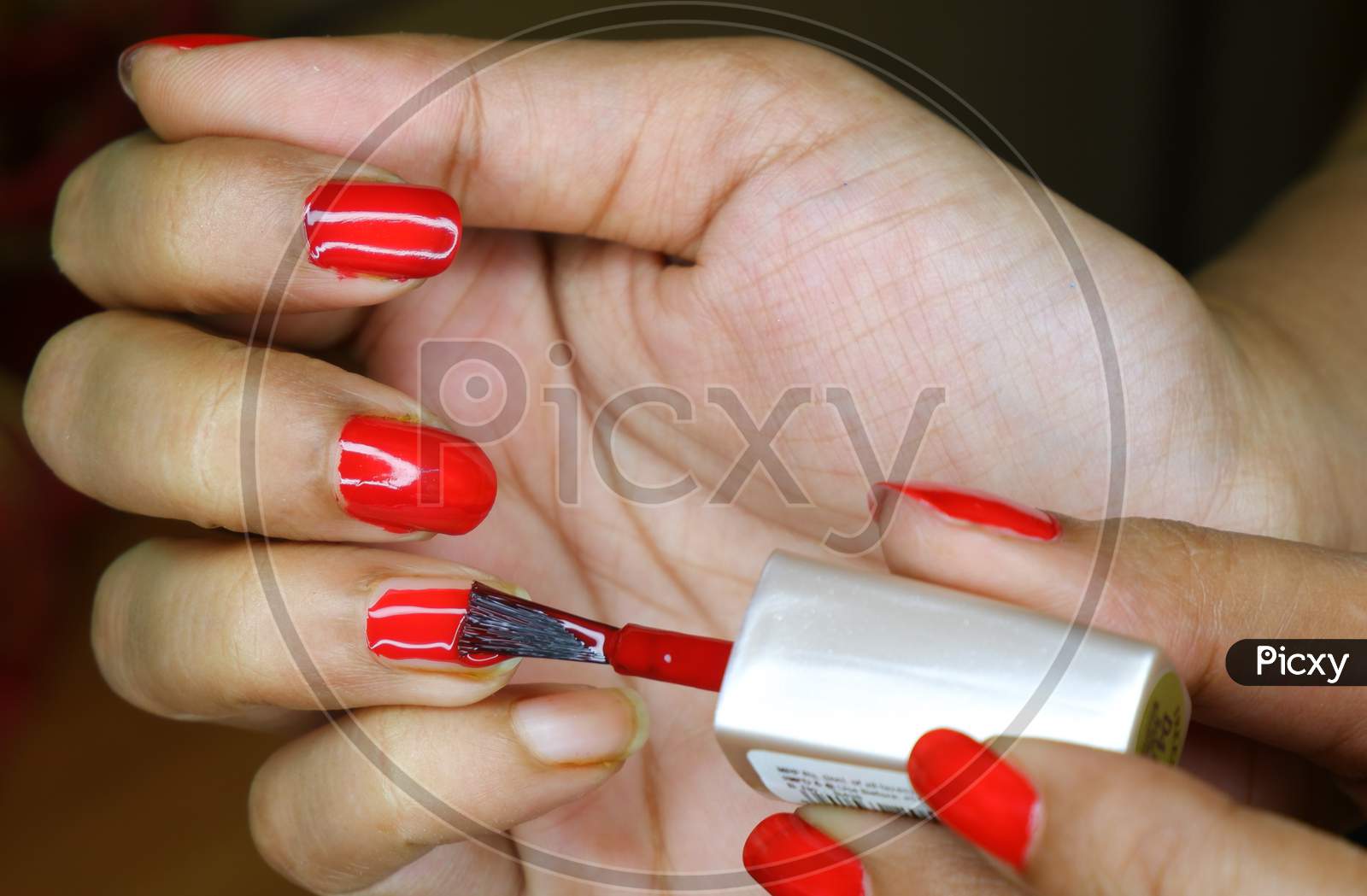 Image of Woman Putting Red Colour Nail Polish On Her Nails.-ZF109297-Picxy