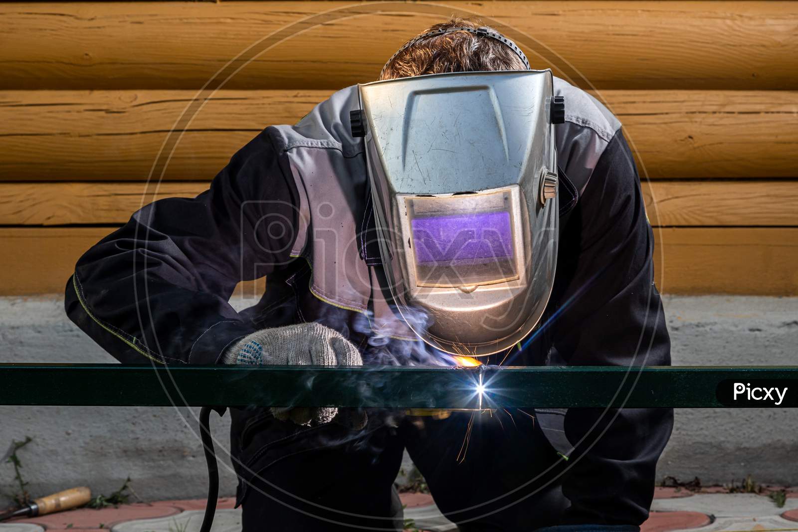 Image of Worker Male Welder At A Construction Site Welds A Metal ...