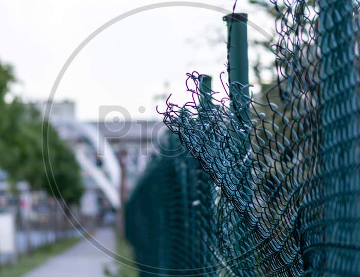 Image of Green damaged wire-mesh fence is ruined after collision with ...