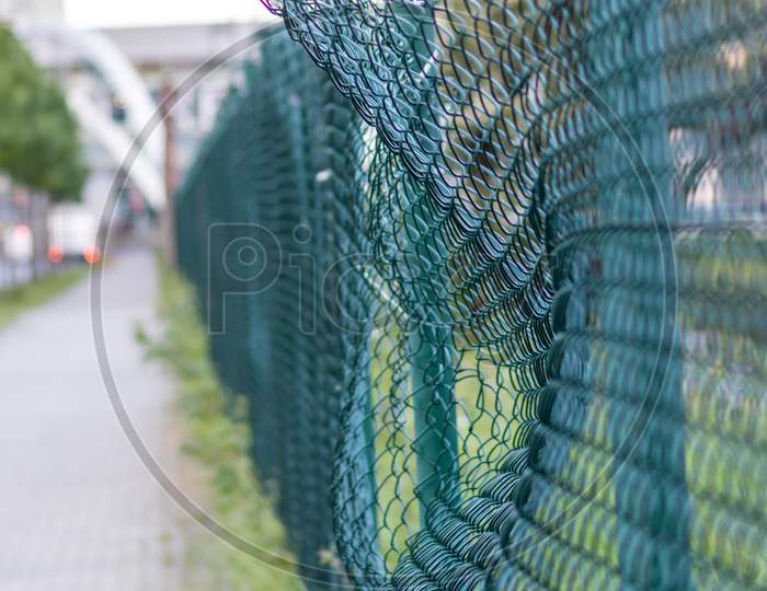 Image of Green damaged wire-mesh fence is ruined after collision with ...